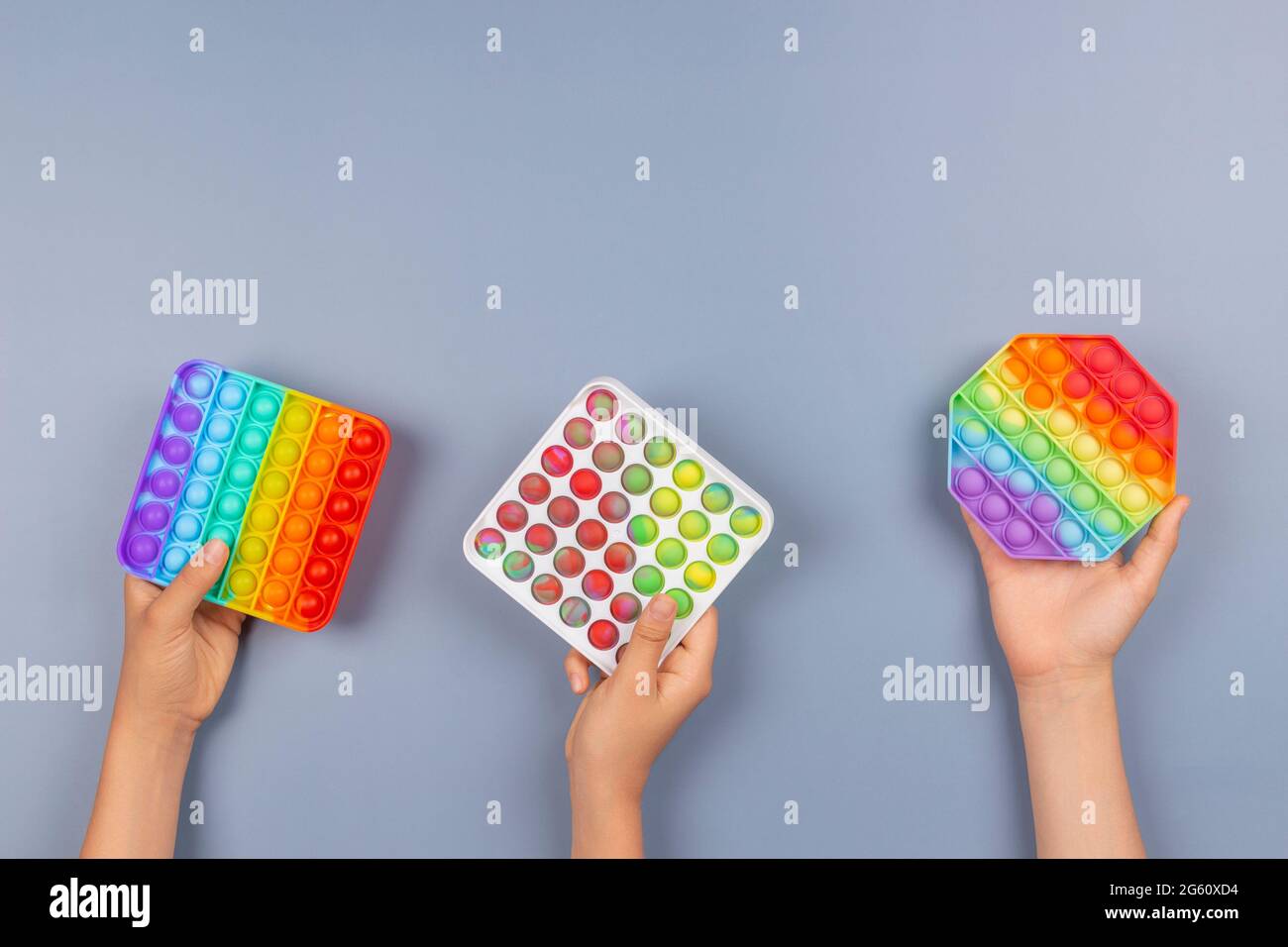 Many hands holding pop it fidget toys on blue background. Push pop-it ...