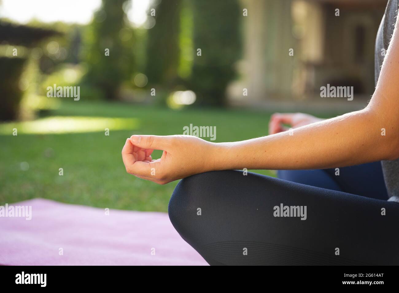 Midsection of caucasian woman practicing yoga in garden, sitting and ...