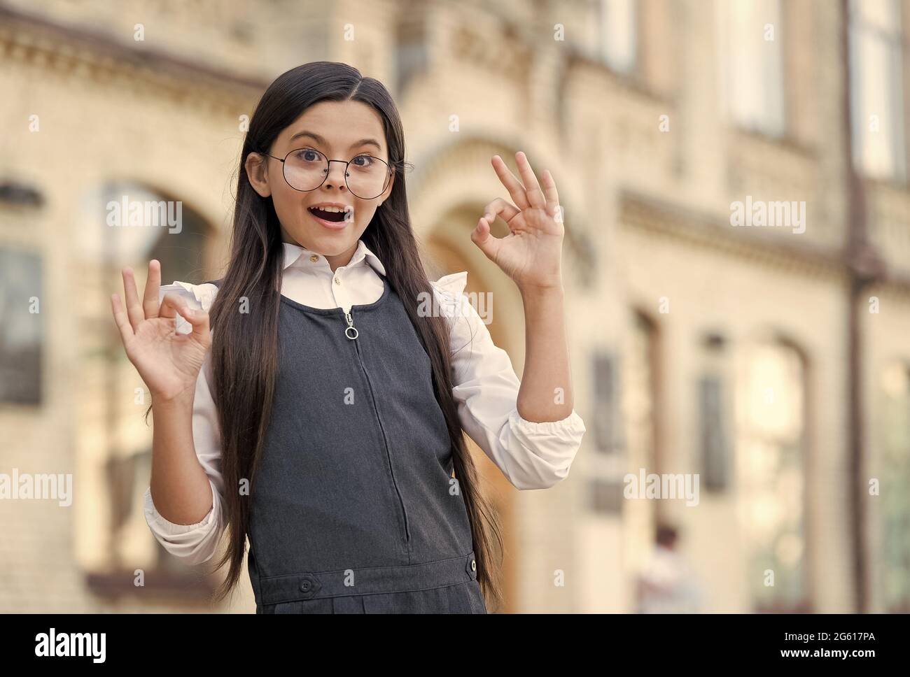 Its okay. Happy kid in uniform show OK hands outdoors. OK sign or ring ...