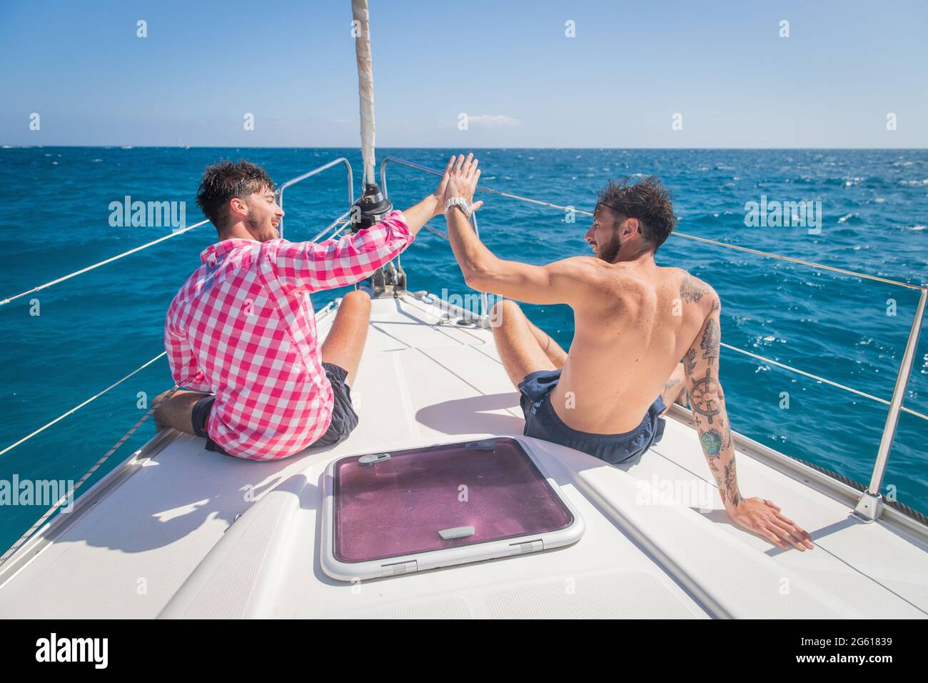 two friends on a boat are happy and do high five, the day is beautiful ...