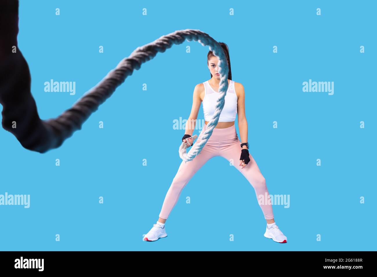 Fit young woman training hard with a rope making exercises in the gym ...