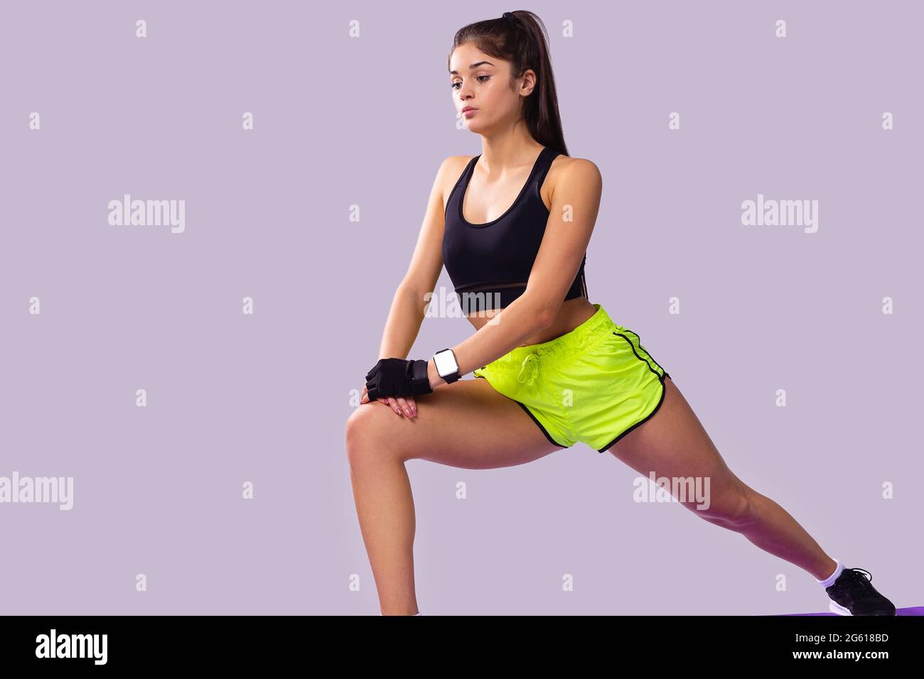 Beautiful female in sneakers and sports clothes exercising to make her ...