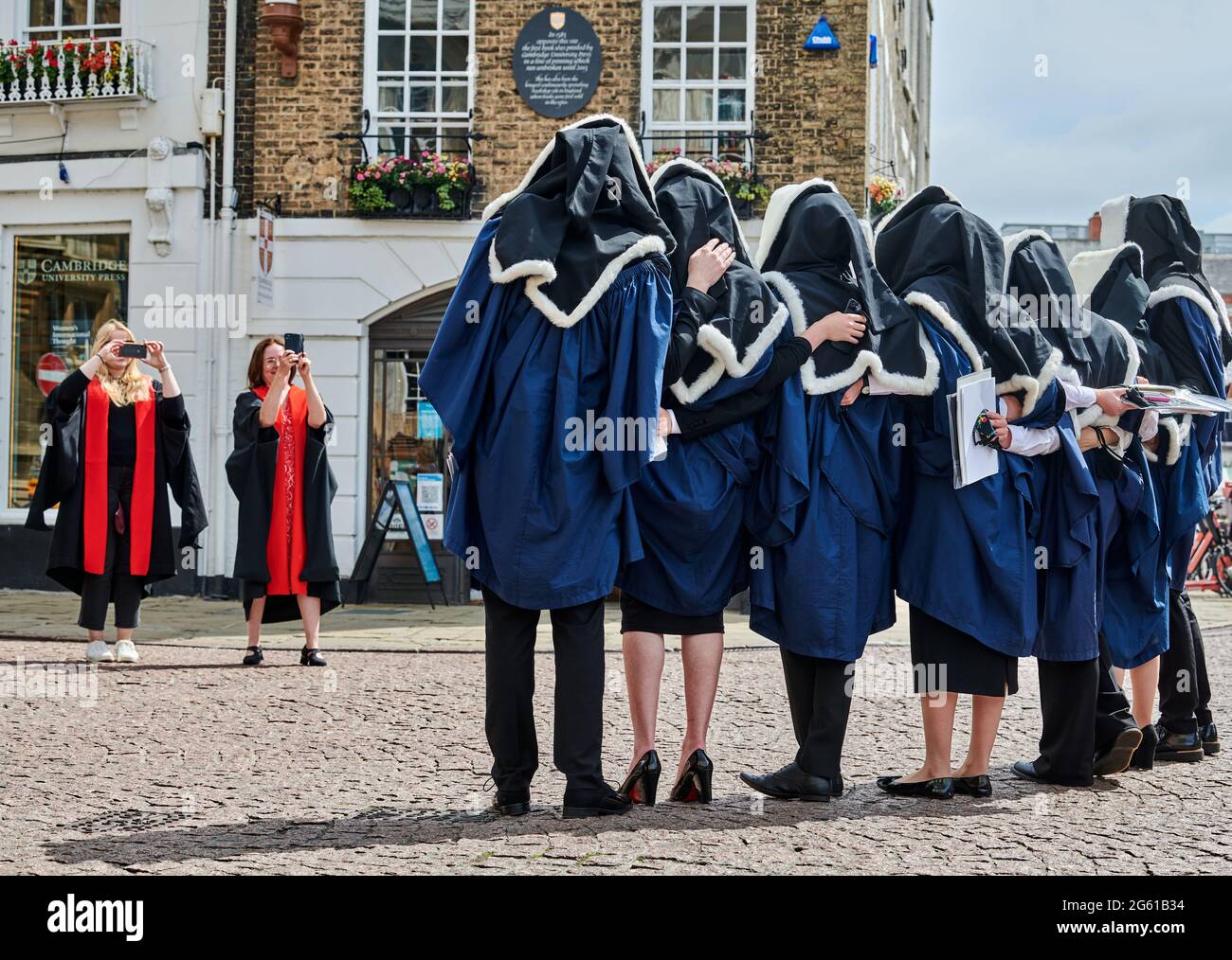 Students in their academic gowns pose for a photograph after graduation ...