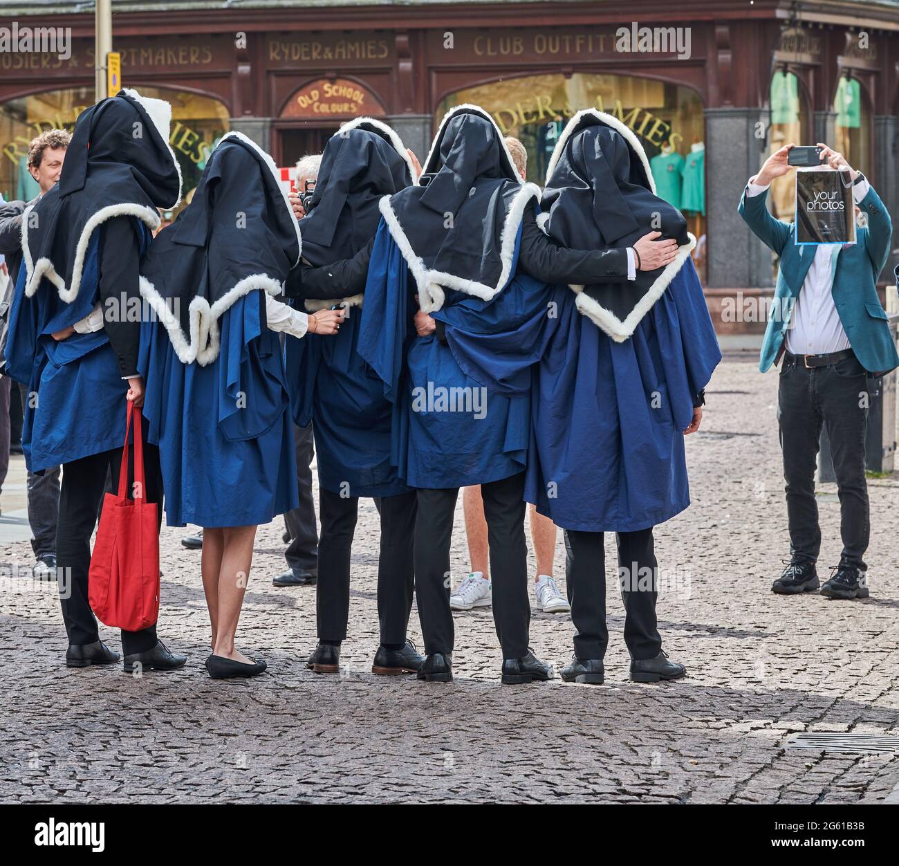 Students in their academic gowns pose for a photograph after graduation ...