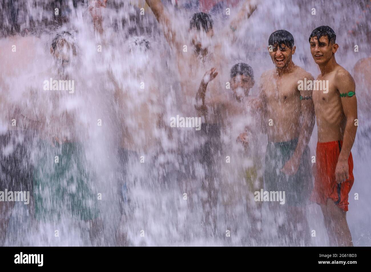 Baghdad, Iraq. 01st July, 2021. Iraqis cool off under showers of water ...