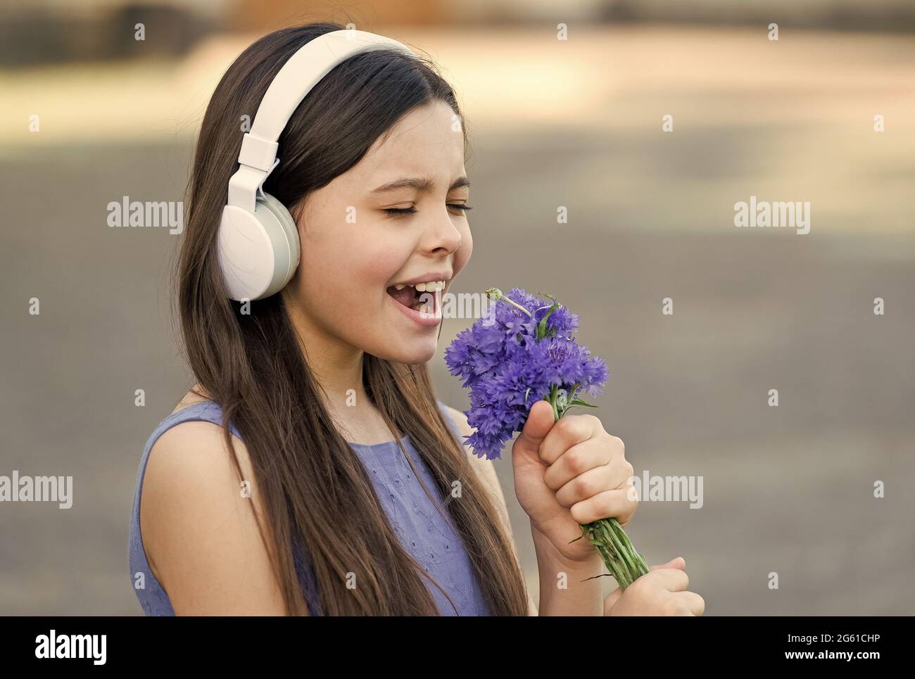 Kiddie song. Happy kid sing song outdoors. Using flowers as microphone ...