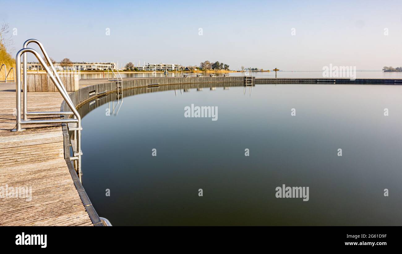 Wooden platform that forms a natural swimmingpool with metal stairs and ...