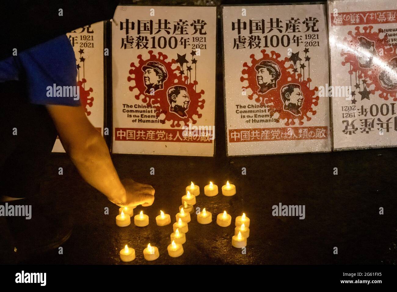 A protester lighting up candles in front of the anti-CCP placards ...
