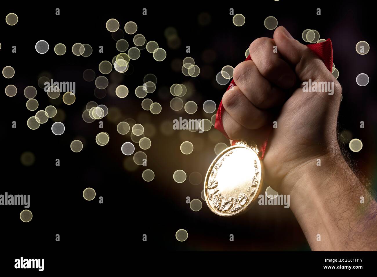 hand holding a gold medal on black with blank face for text, concept ...