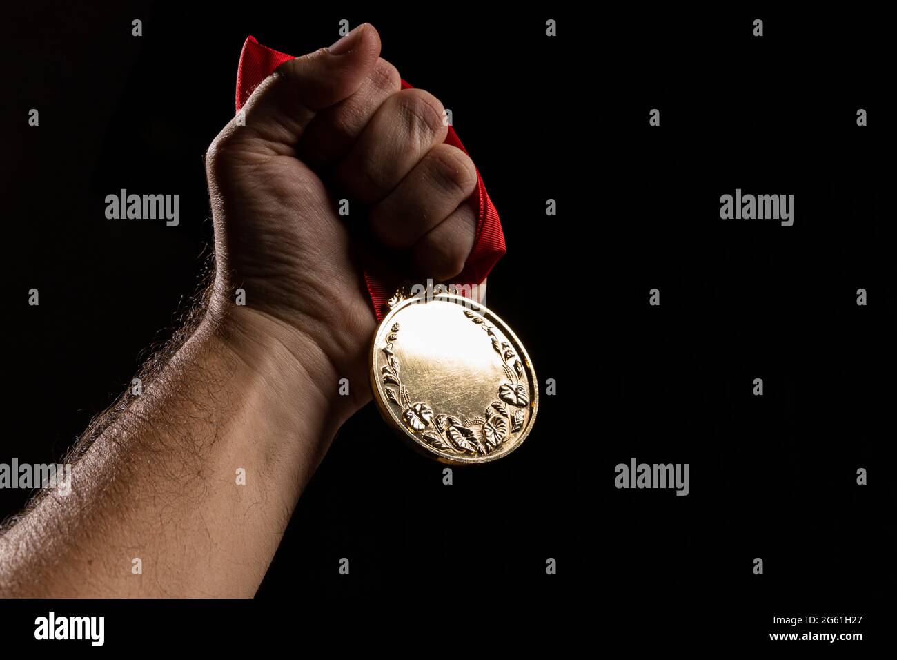 hand holding a gold medal on black with blank face for text, concept ...