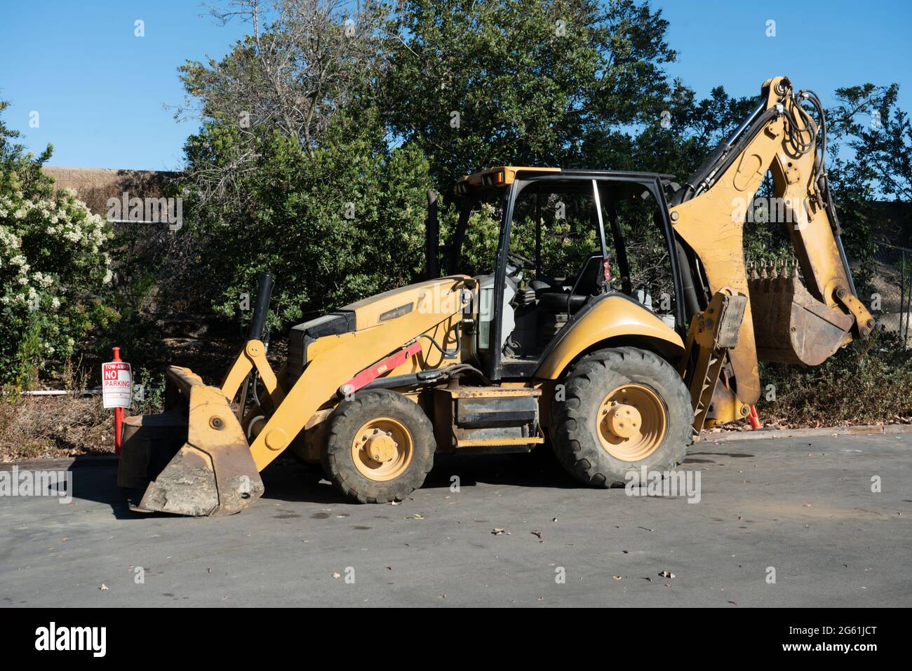 Construction backhoe loader parked on asphalt lot Stock Photo - Alamy