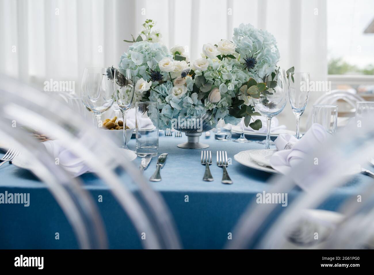 Luxurious round table set for an event, decorated with lush blue ...