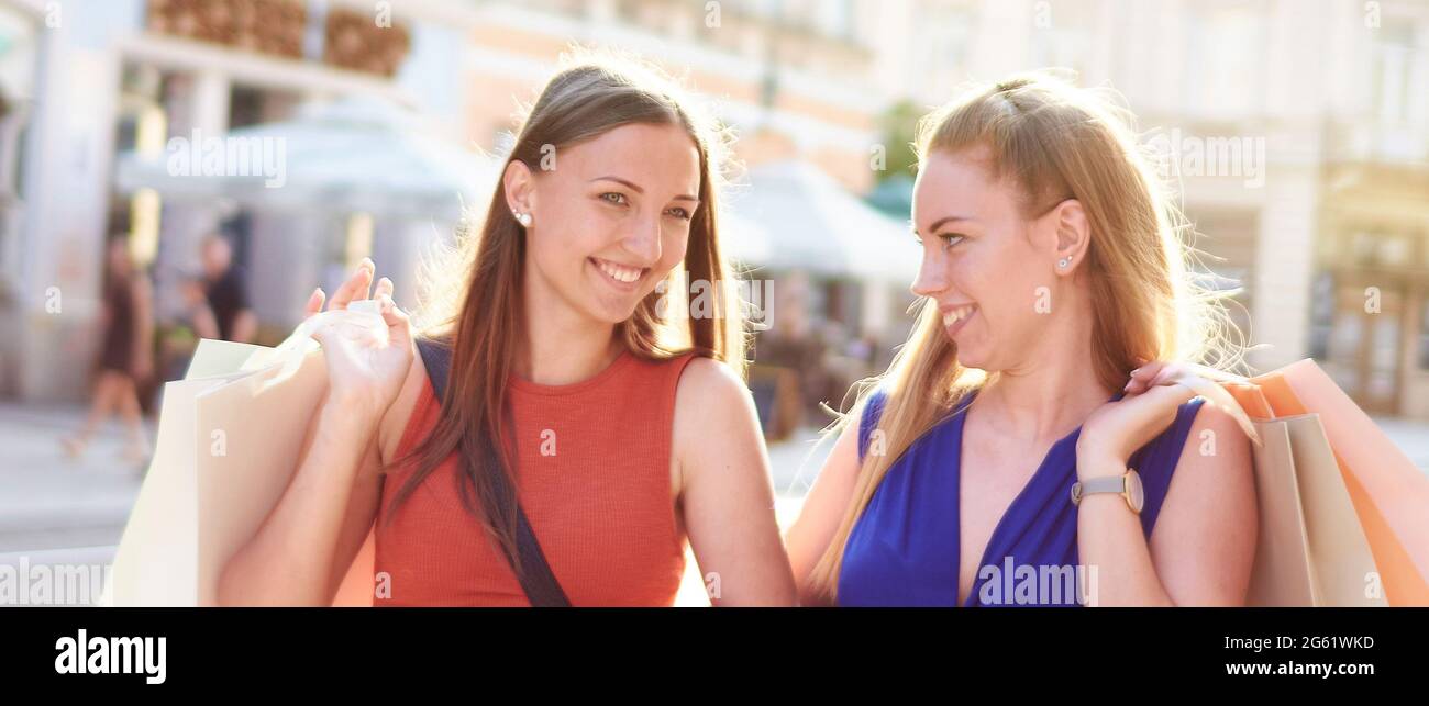 Cheerful happy shopaholic women friends walking on a city street with ...