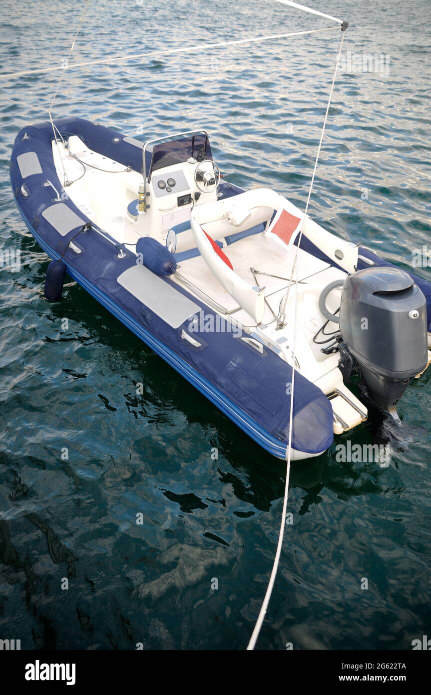 Modern inflatable boat with engine in the sea near shore, blue white ...