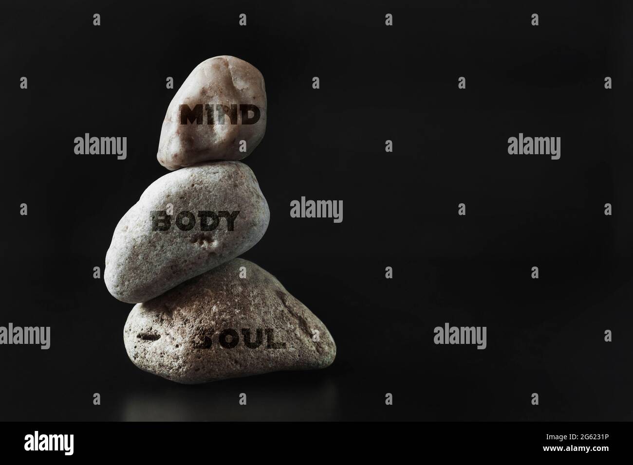 Three stones stand on top of each other keeping their balance. Dark ...