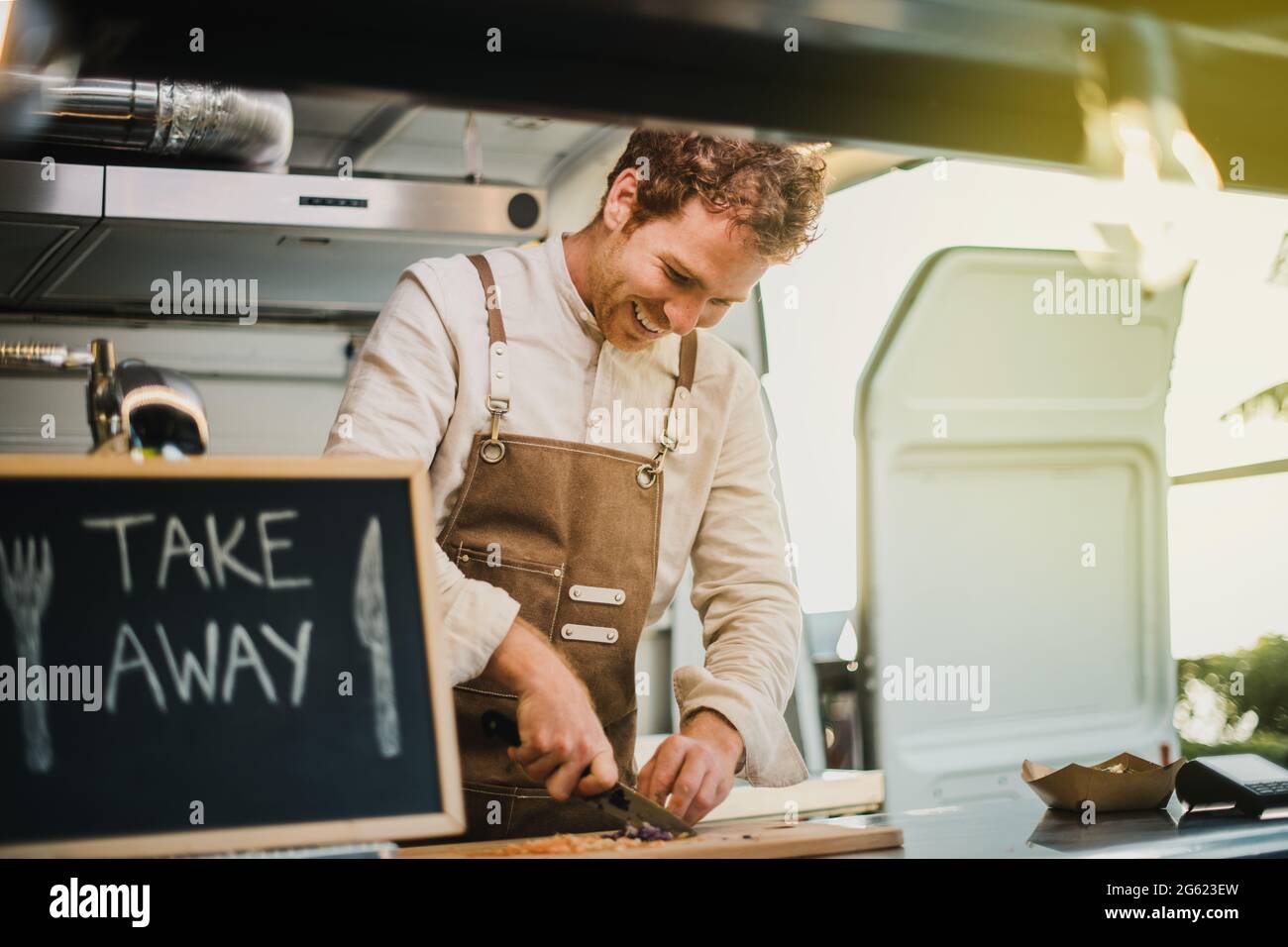 Young chef cooking inside vegan food truck restaurant - Focus on face ...