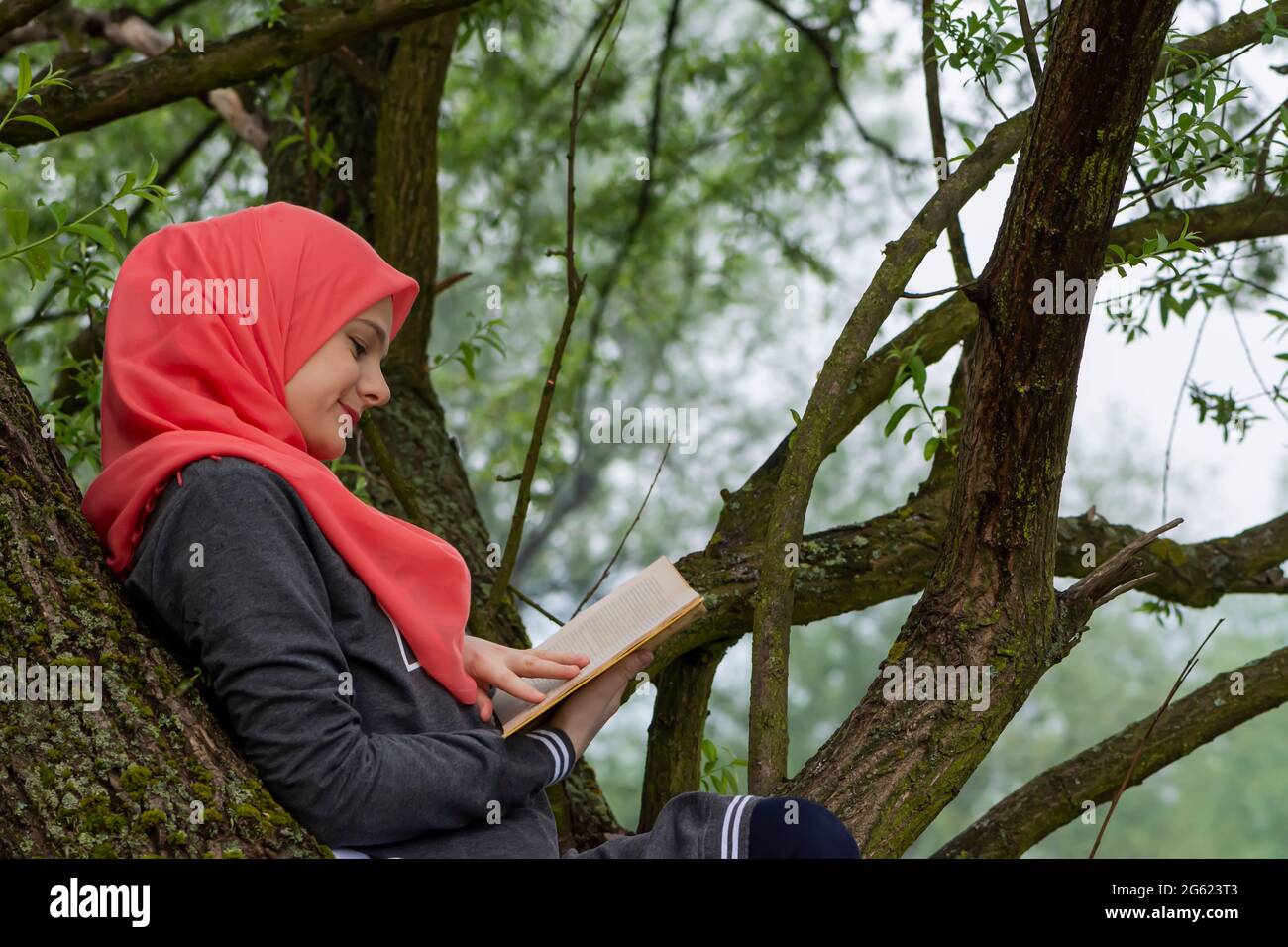 Muslim female student reading a book in nature, outdoor Stock Photo - Alamy