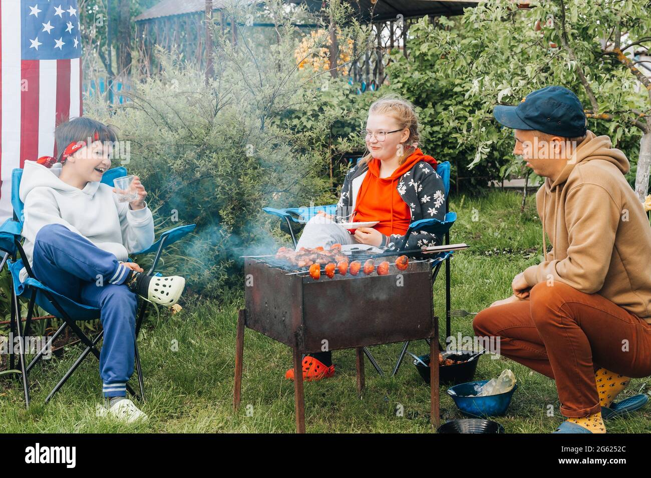 Happy young family make barbecue together in garden. People barbecuing ...