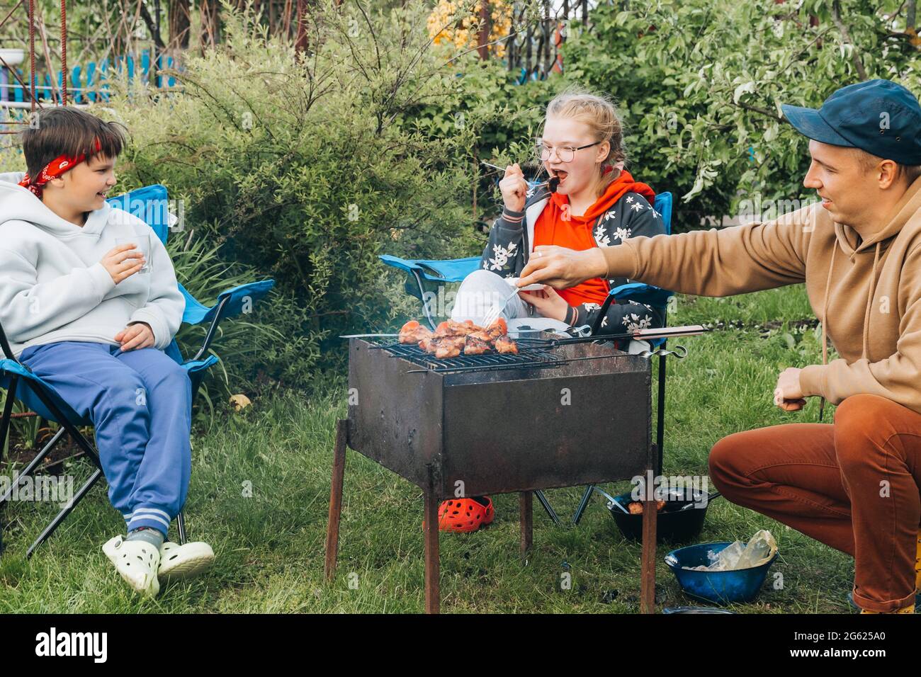 Happy young family make barbecue together in garden. People barbecuing ...