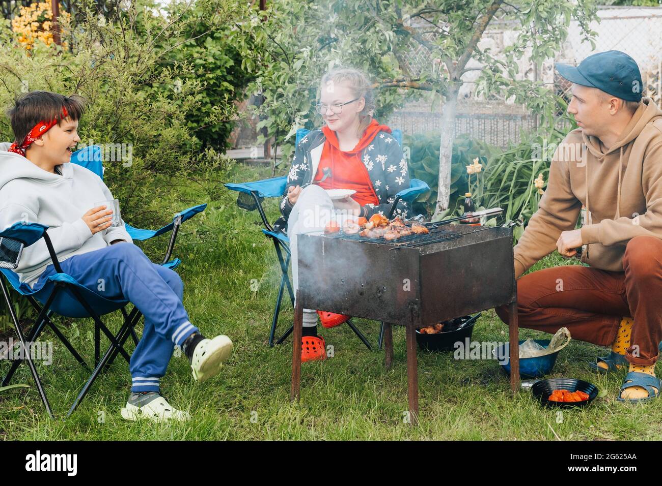 Happy young family make barbecue together in garden. People barbecuing ...