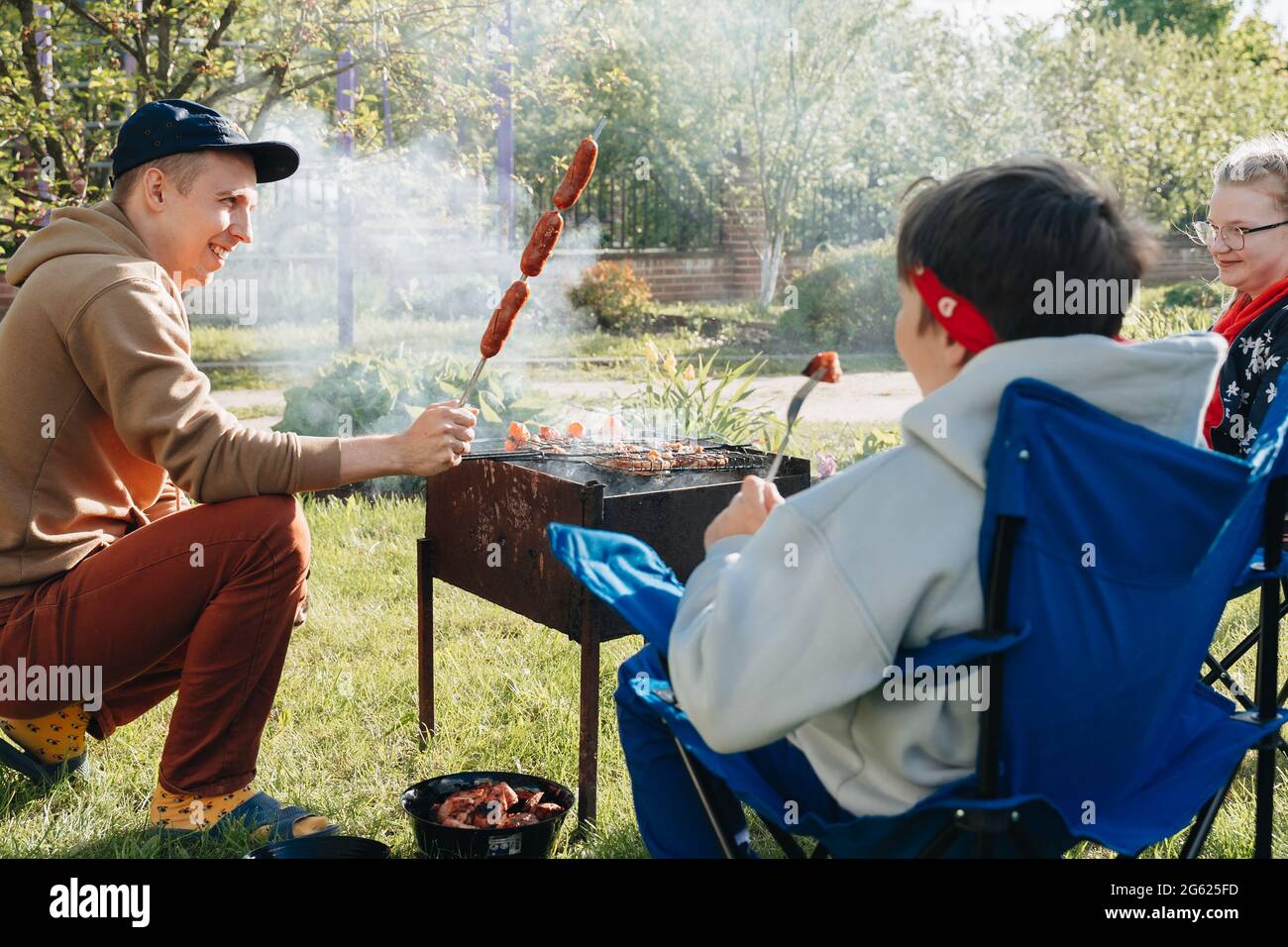 Happy young family make barbecue together in garden. People barbecuing ...