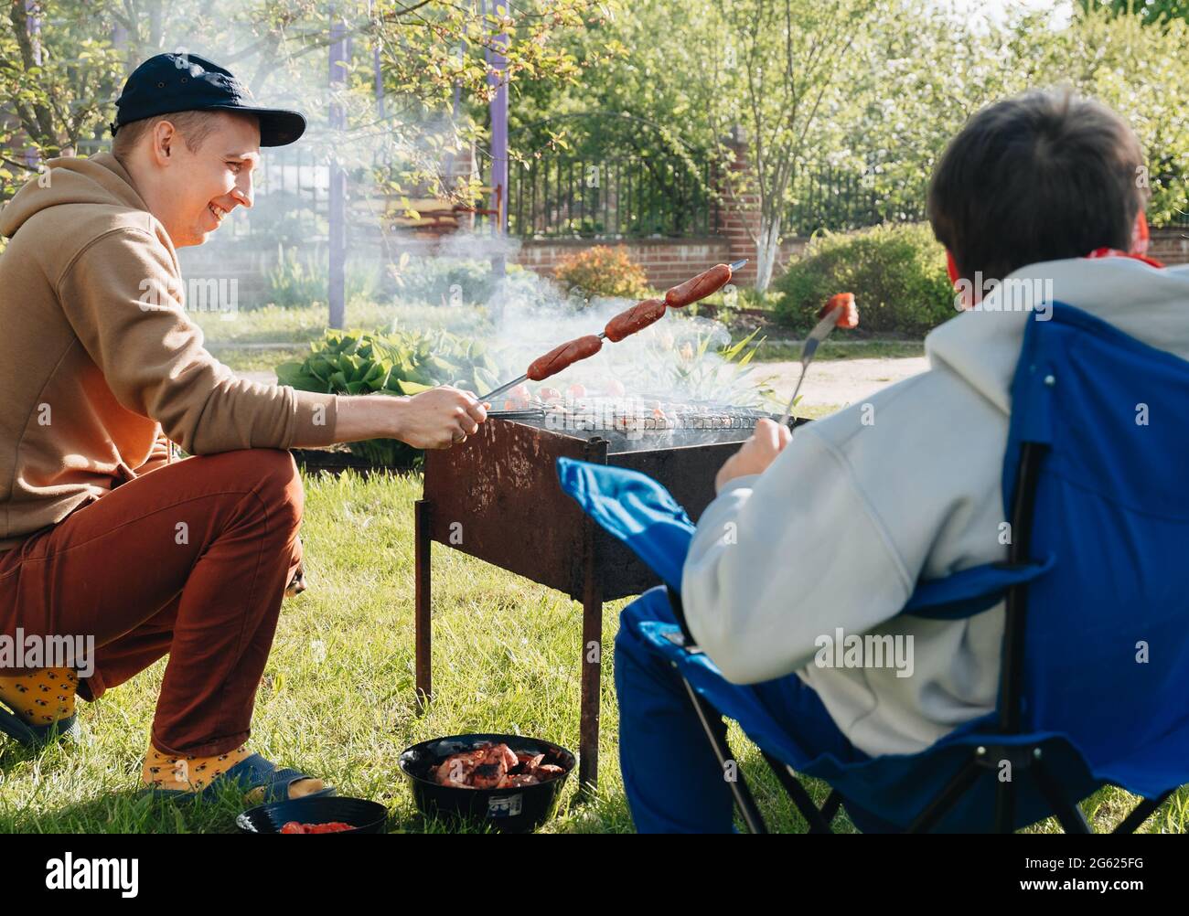 Happy young family make barbecue together in garden. People barbecuing ...