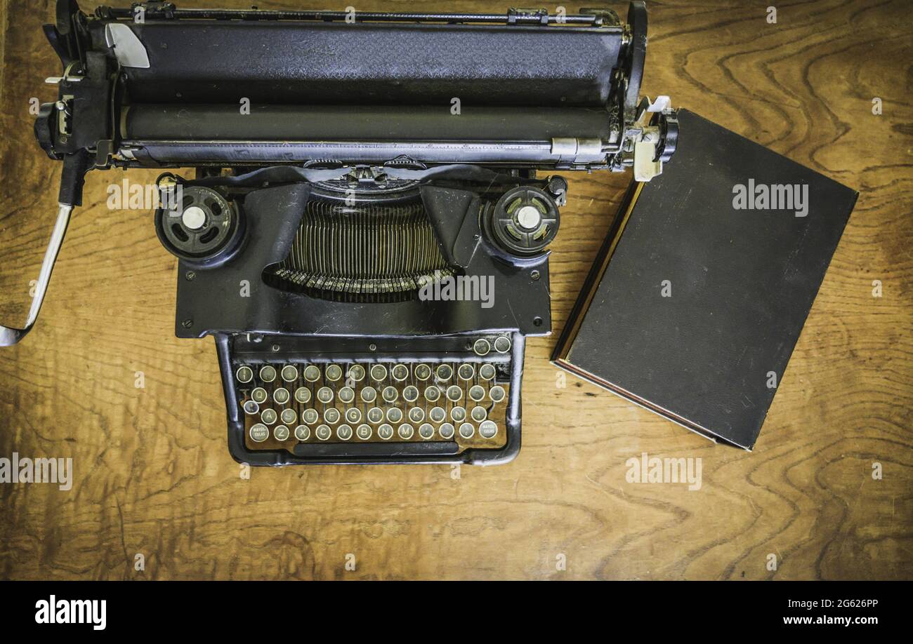 antique black typewriter on a mahogany wood desk viewed from above ...