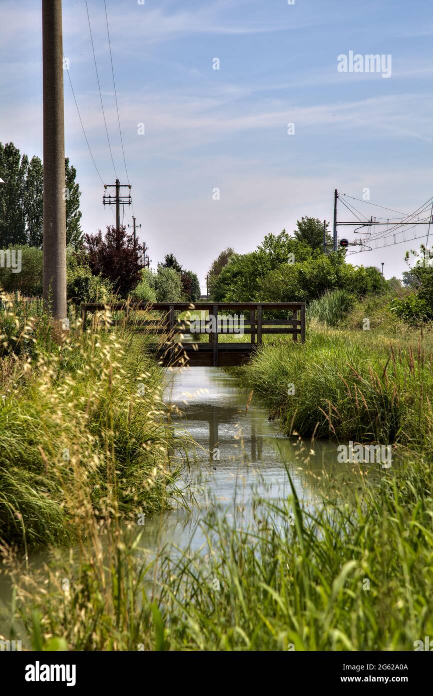 Stream of water with a bridge next to a path in the italian countryside ...