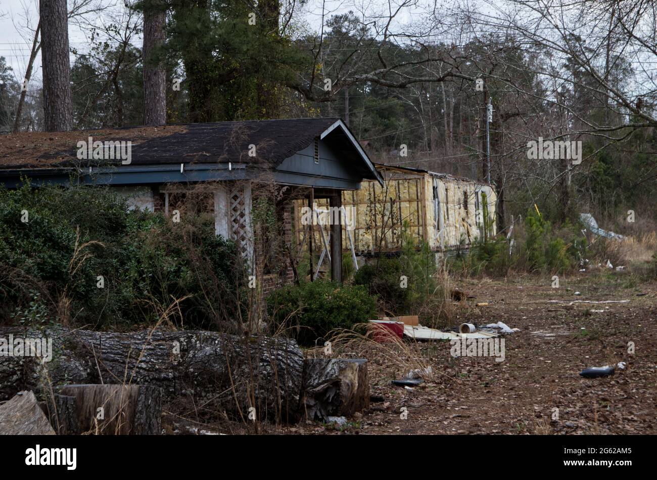 Dilapidated damaged abandoned house and mobile home with trash and ...