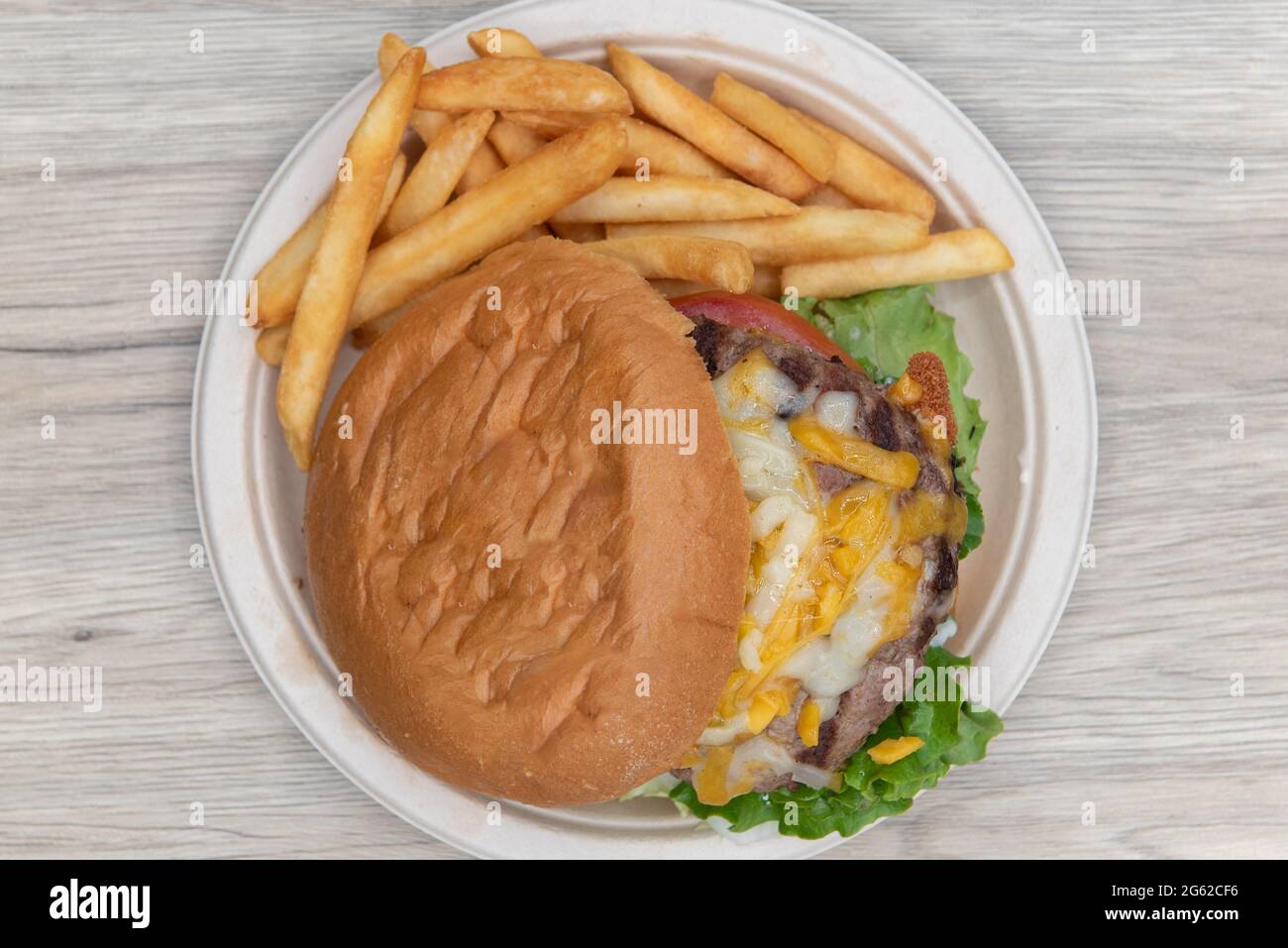 Overhead view of enormous cheeseburger sliding off the bun with a ...