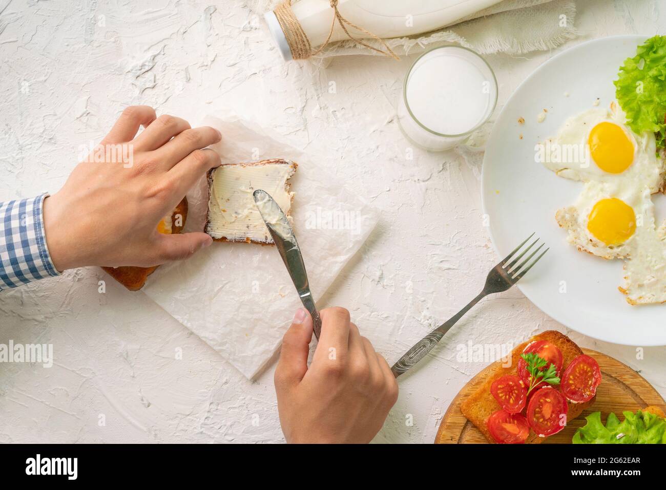 top view person eating breakfast on the white table, using tableware ...
