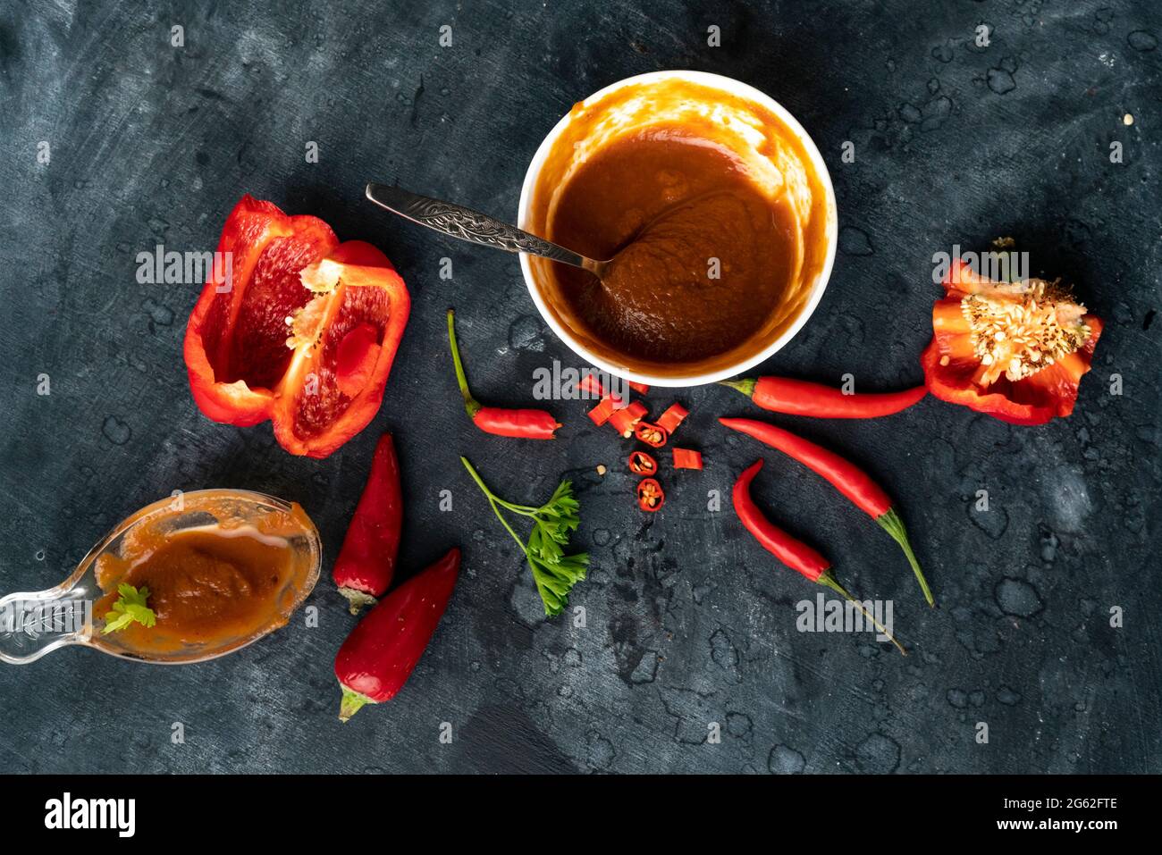 top view of red spicy pepper sauce in a bowl and ingredients for ...