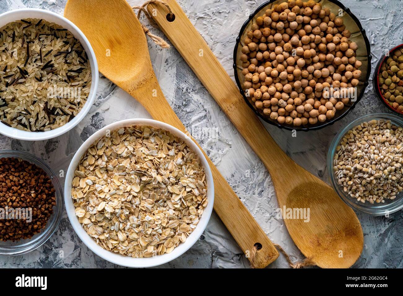 selection of raw uncooked cereals grains in bulbs with chickpeas oat ...