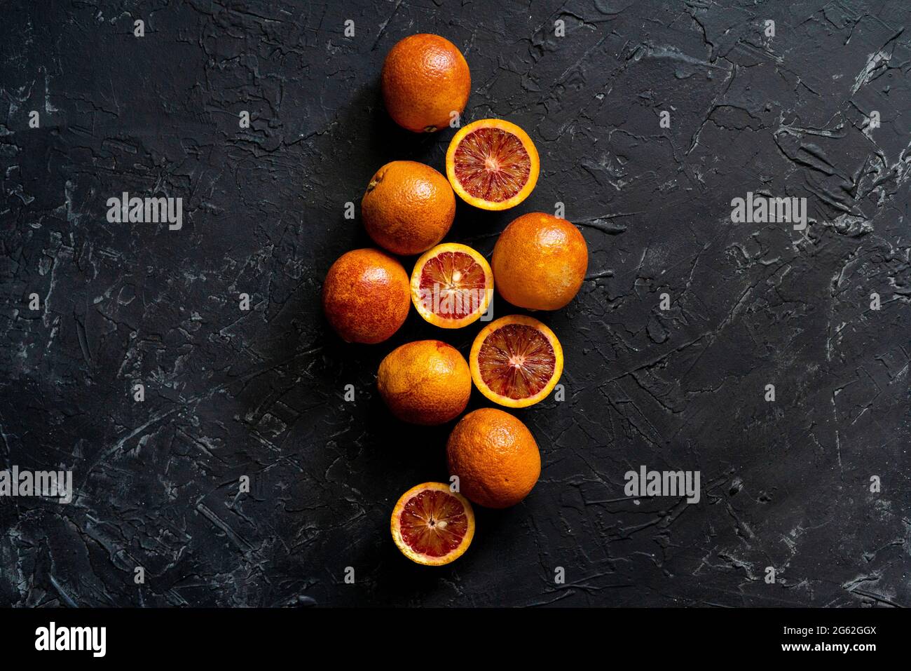flat lay of red sliced exotic oranges, dark food on black surface Stock ...