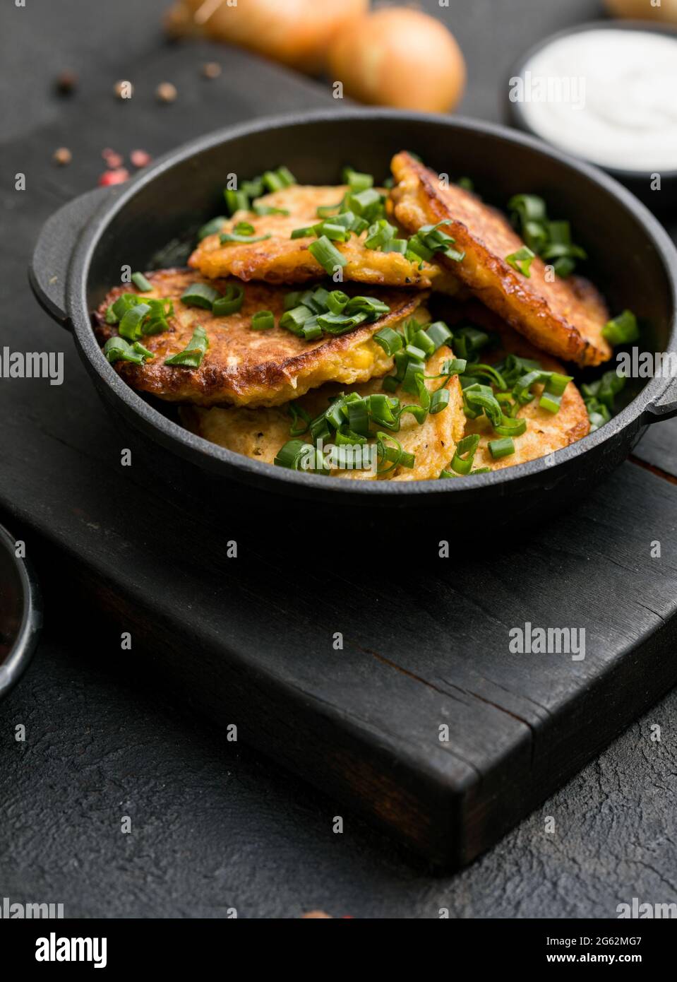 Delicious onion fritters with sour cream and green onion on plate ...