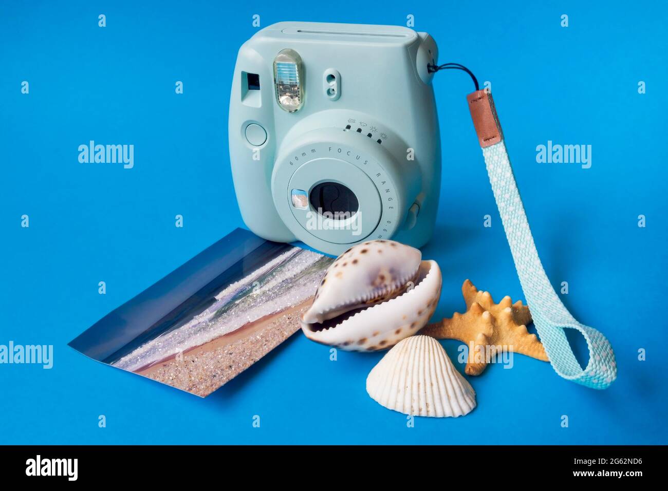 Camera, seashells and postcard with sea view on a blue background ...