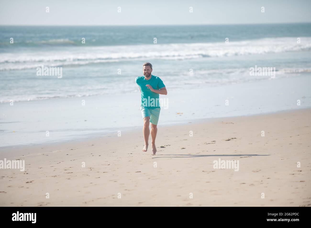 Morning jogging on a sandy beach near sea or ocean. Man running on ...