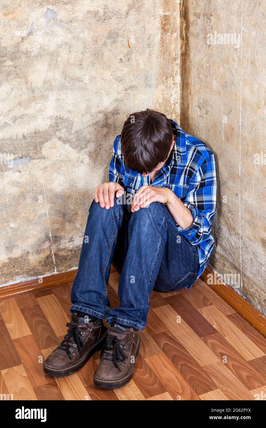 Sad Teenager in the Corner on the Floor by the Old Wall Stock Photo - Alamy