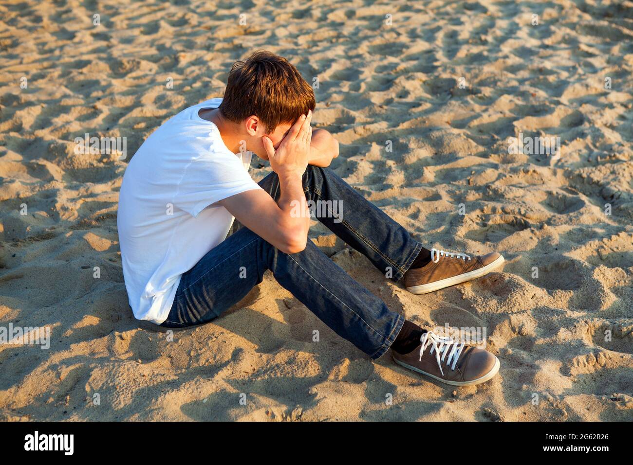 Sad Young Man sit on the Sand Stock Photo - Alamy