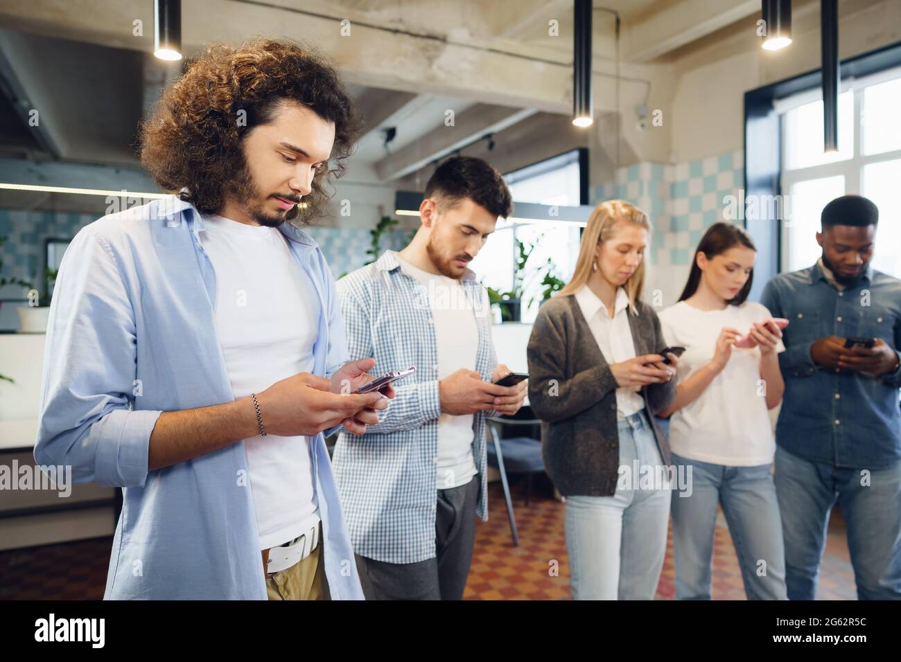 Diverse young people colleagues working on mobile phones together in ...