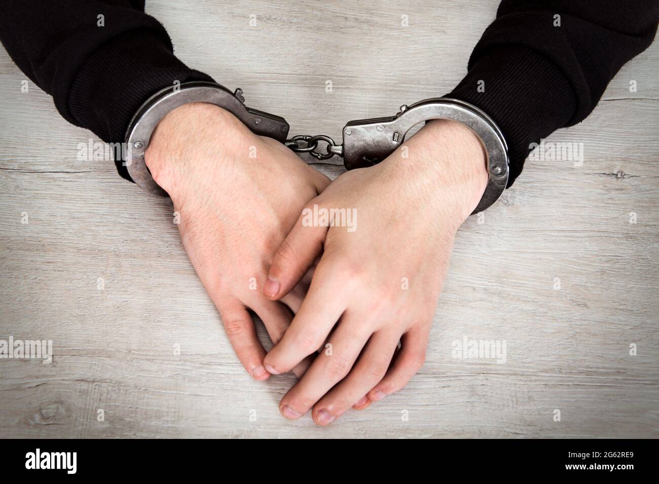 Person in Handcuffs on the Table closeup Stock Photo - Alamy