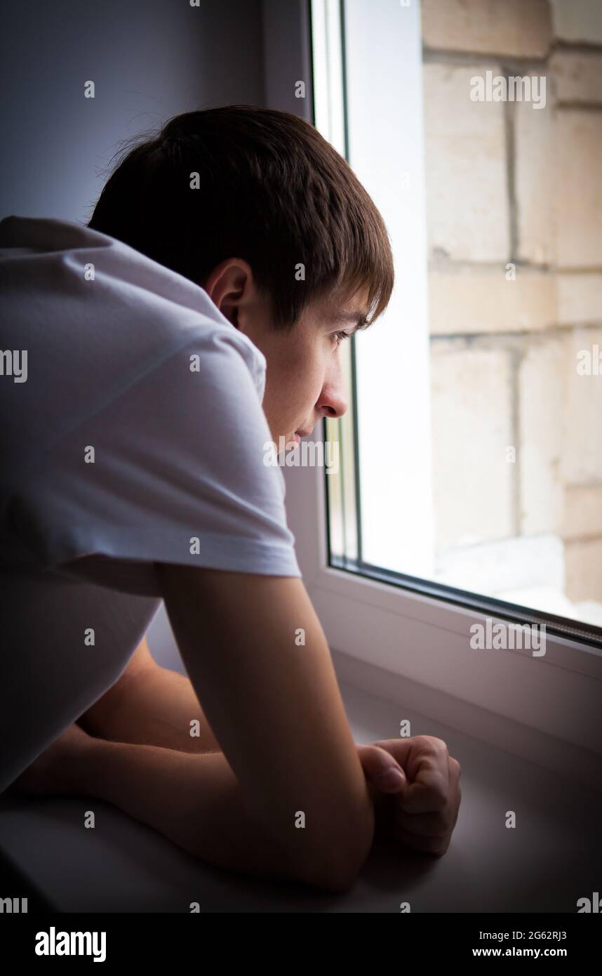 Sad Young Man by the Window in the Room Stock Photo - Alamy