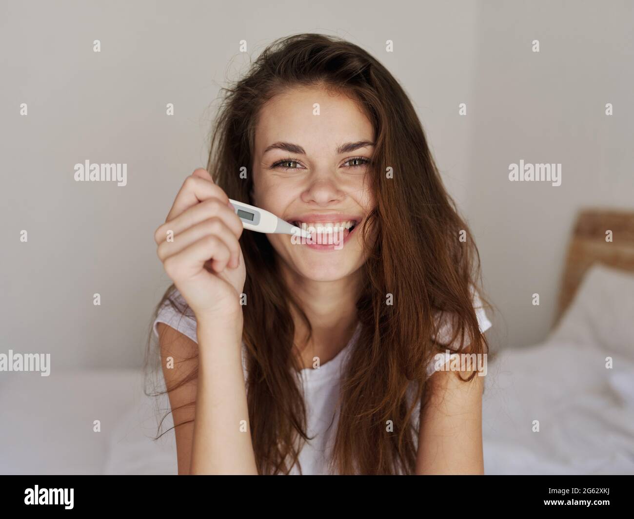 cheerful woman holding a thermometer in her mouth smile positive test ...