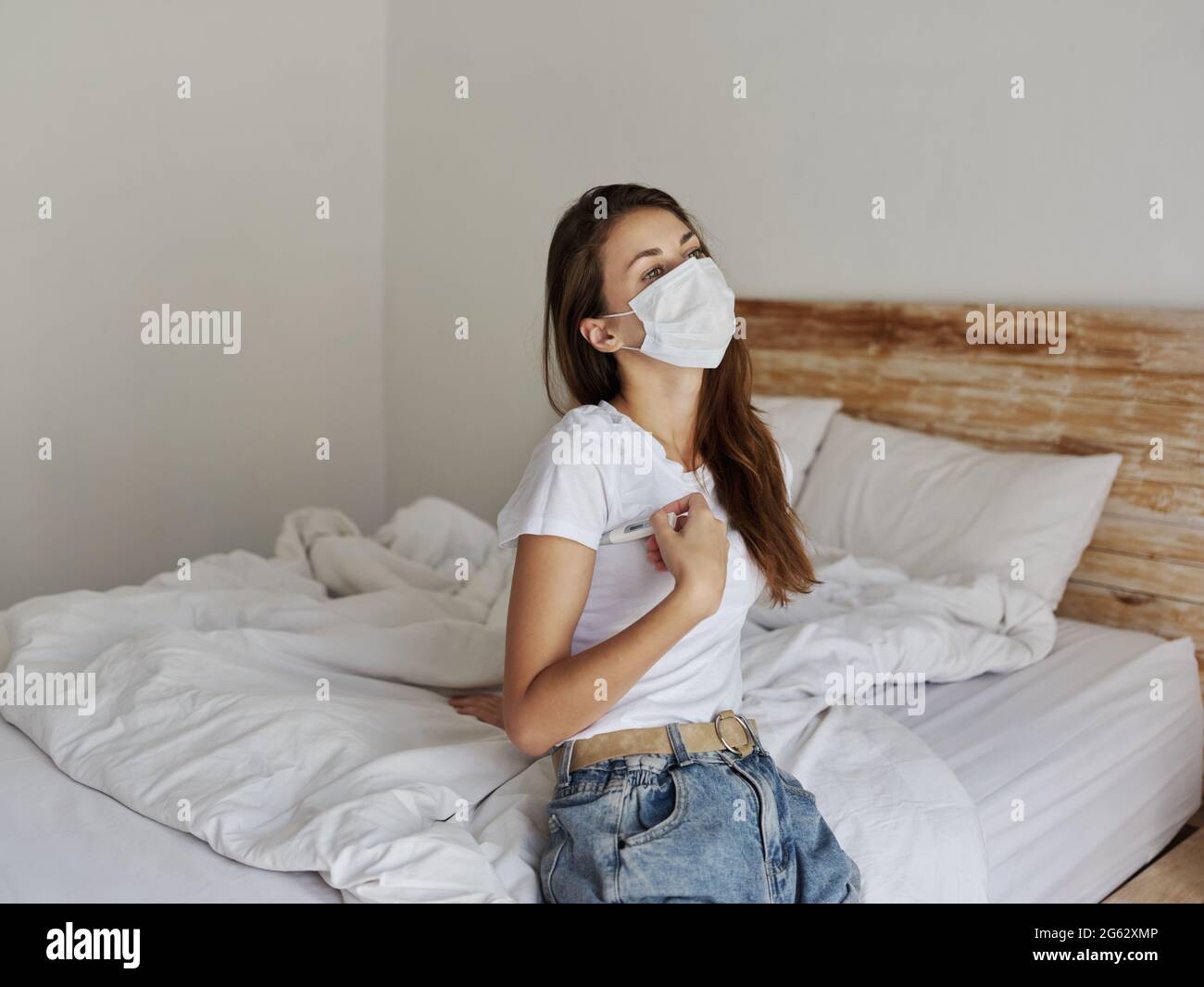 woman in medical mask checking temperature with thermometer under her ...