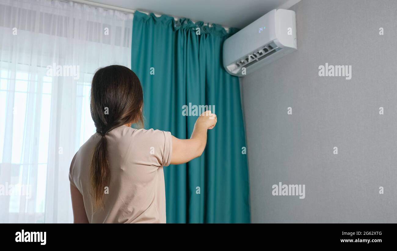 brunette woman turns on the air conditioner, back view Stock Photo - Alamy
