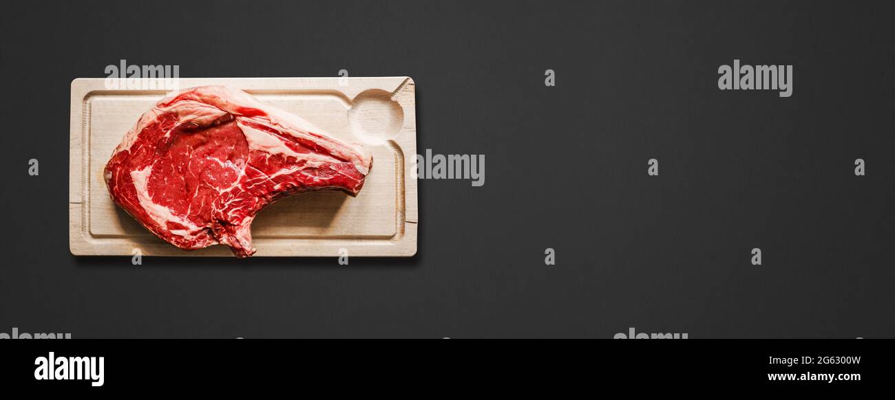 Raw beef prime rib and wooden cutting board isolated on black ...