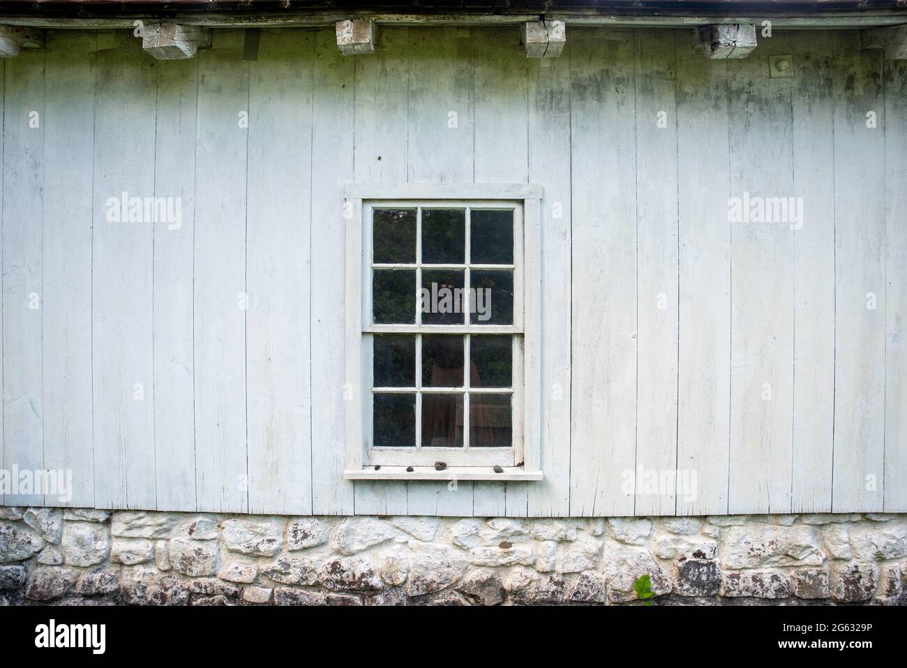 White window in the center of a whitewashed colonial home exterior ...