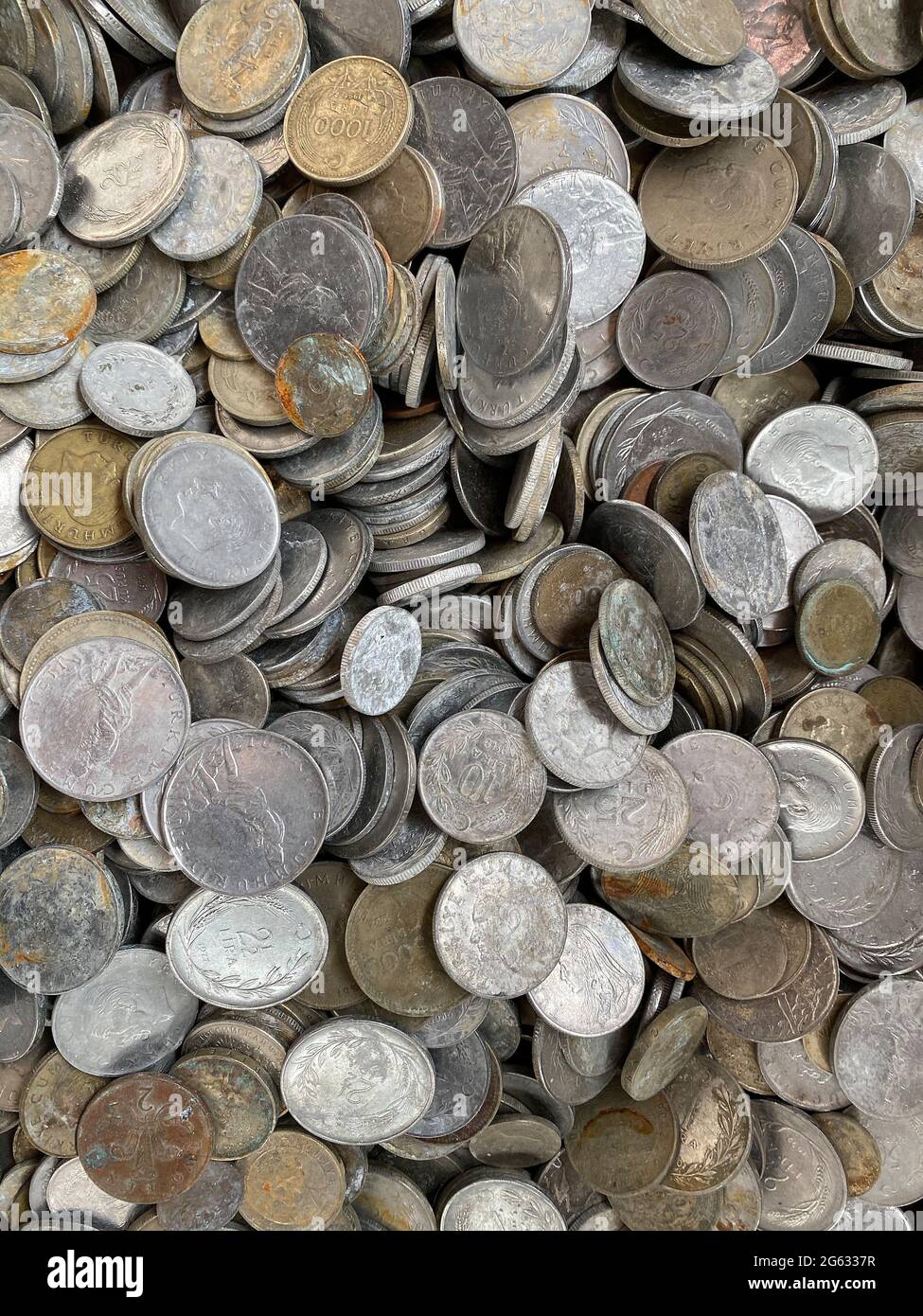 Top view arrangement of many weathered coins of different values heaped ...