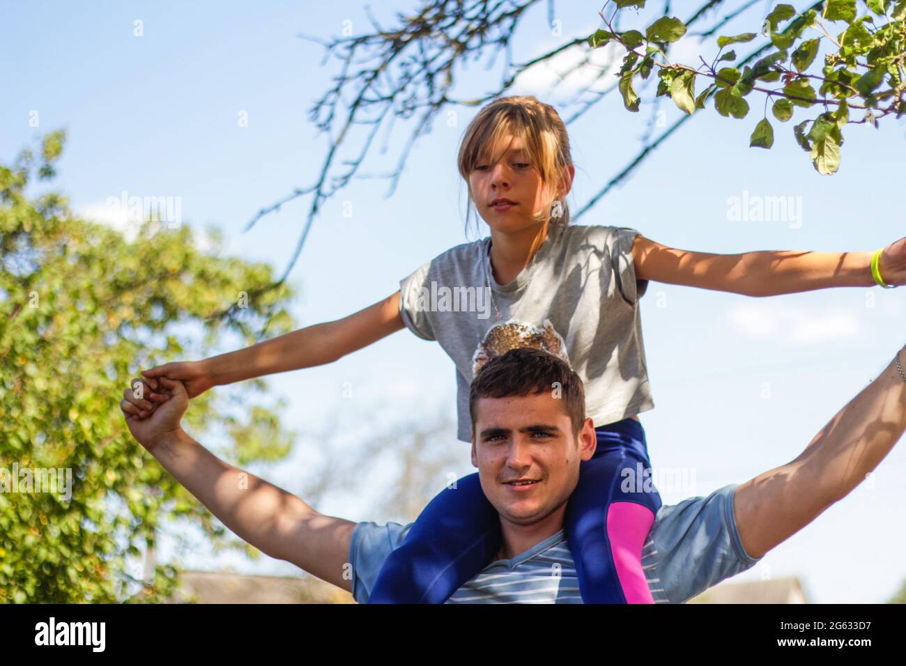 Defocused brother riding sister on back. Portrait of happy girl on man ...