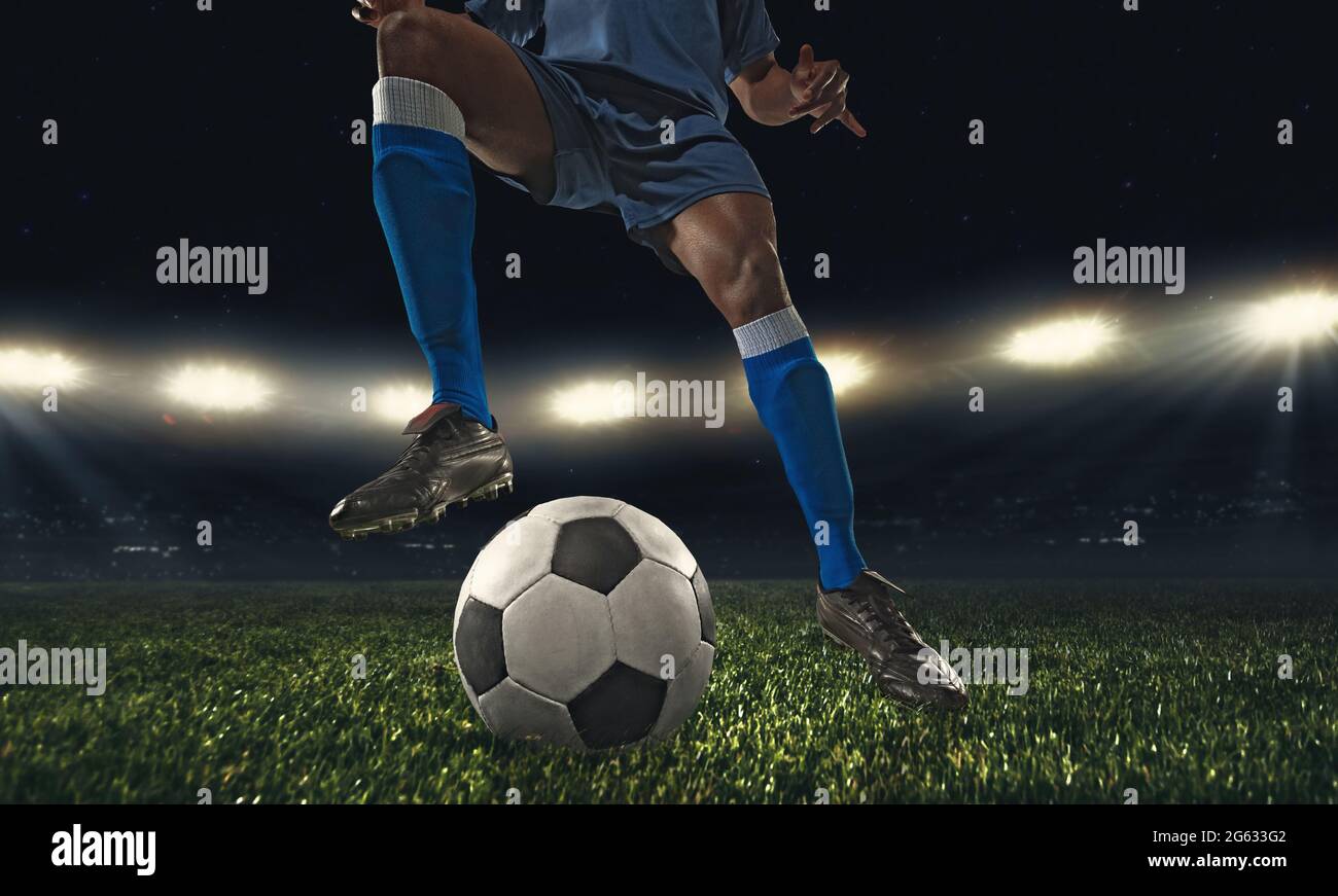 Cropped male soccer, football player kicking ball at the stadium during ...